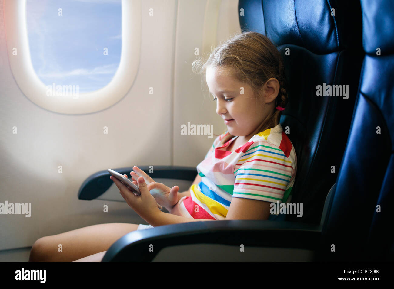 Child in airplane. Kid with mobile phone in air plane in window seat ...