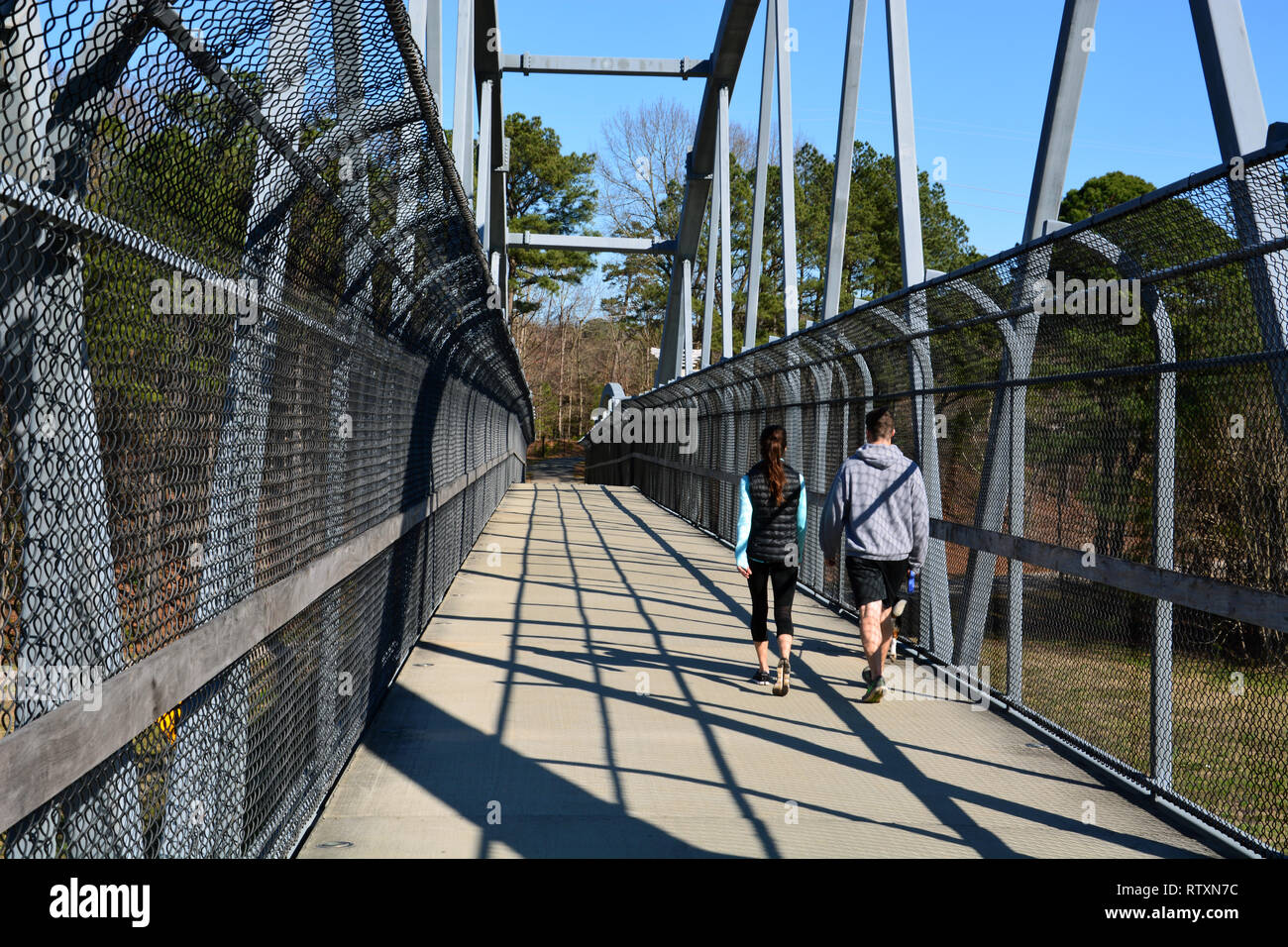 A couple crosses the Reedy Creek Trail pedestrian bridge over the 440 ...