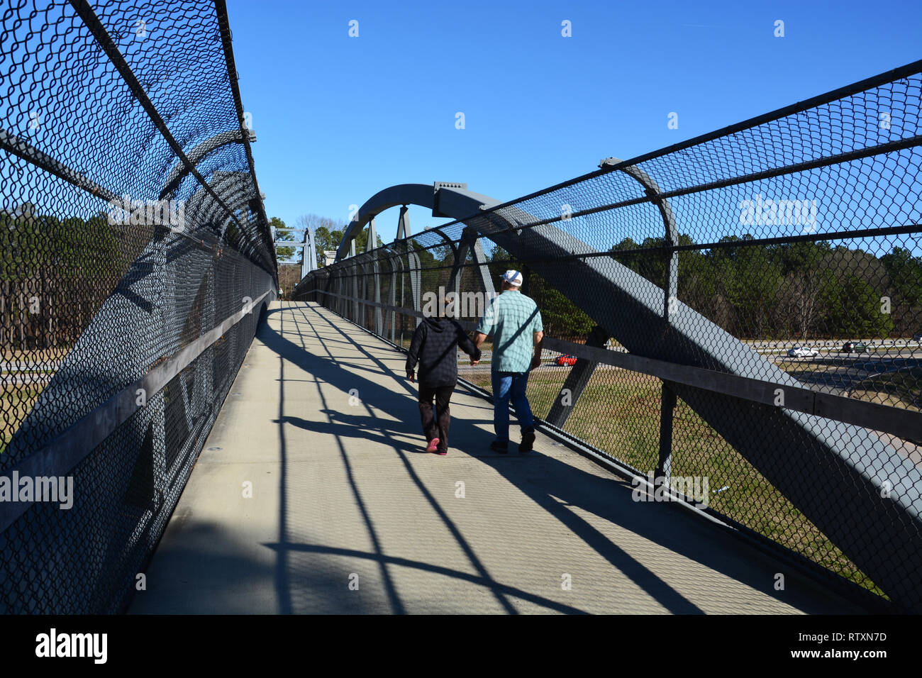 A couple crosses the Reedy Creek Trail pedestrian bridge over the 440 ...