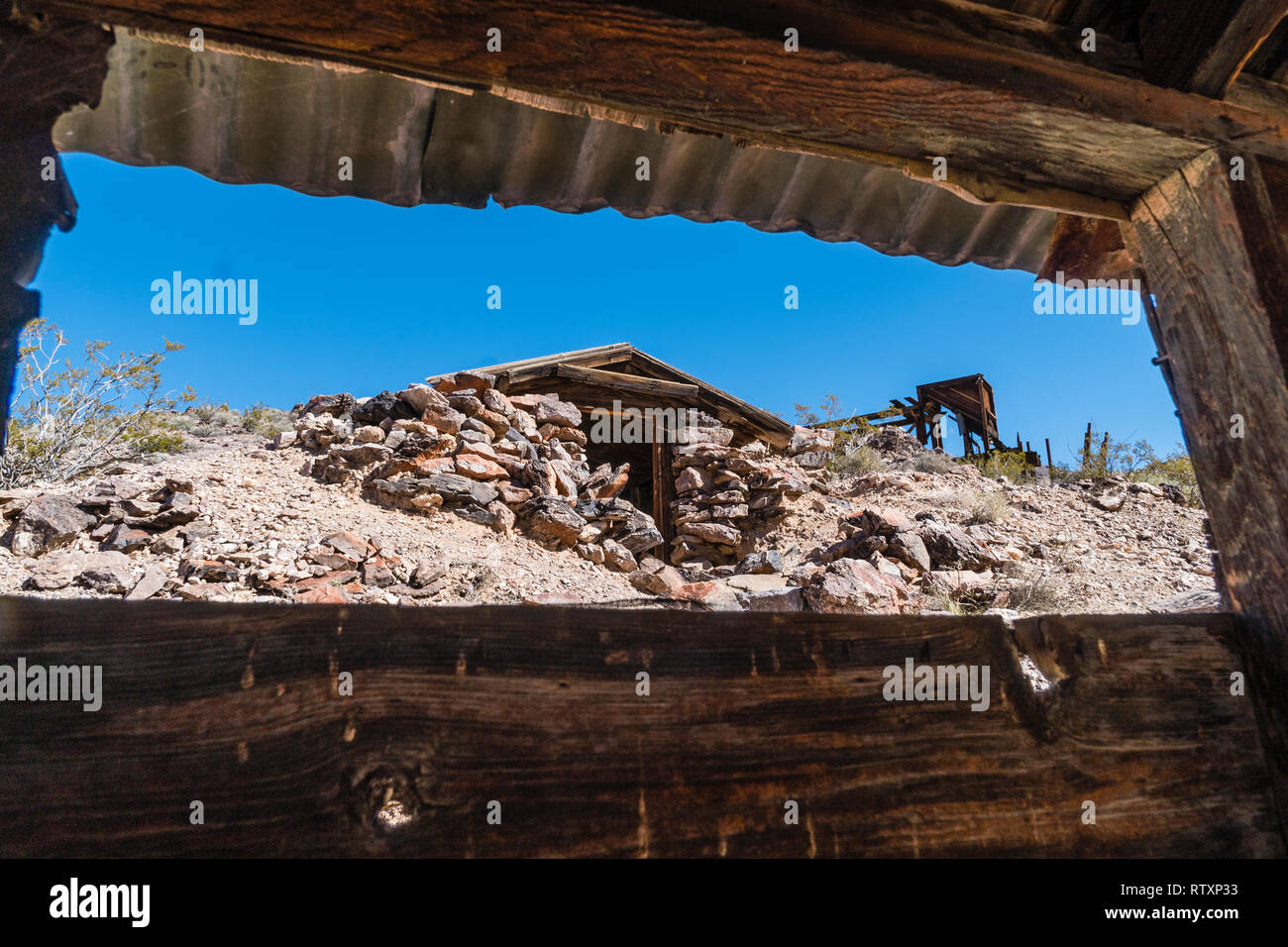 A view from inside a window of a ruin to a stone structure and a tall ...