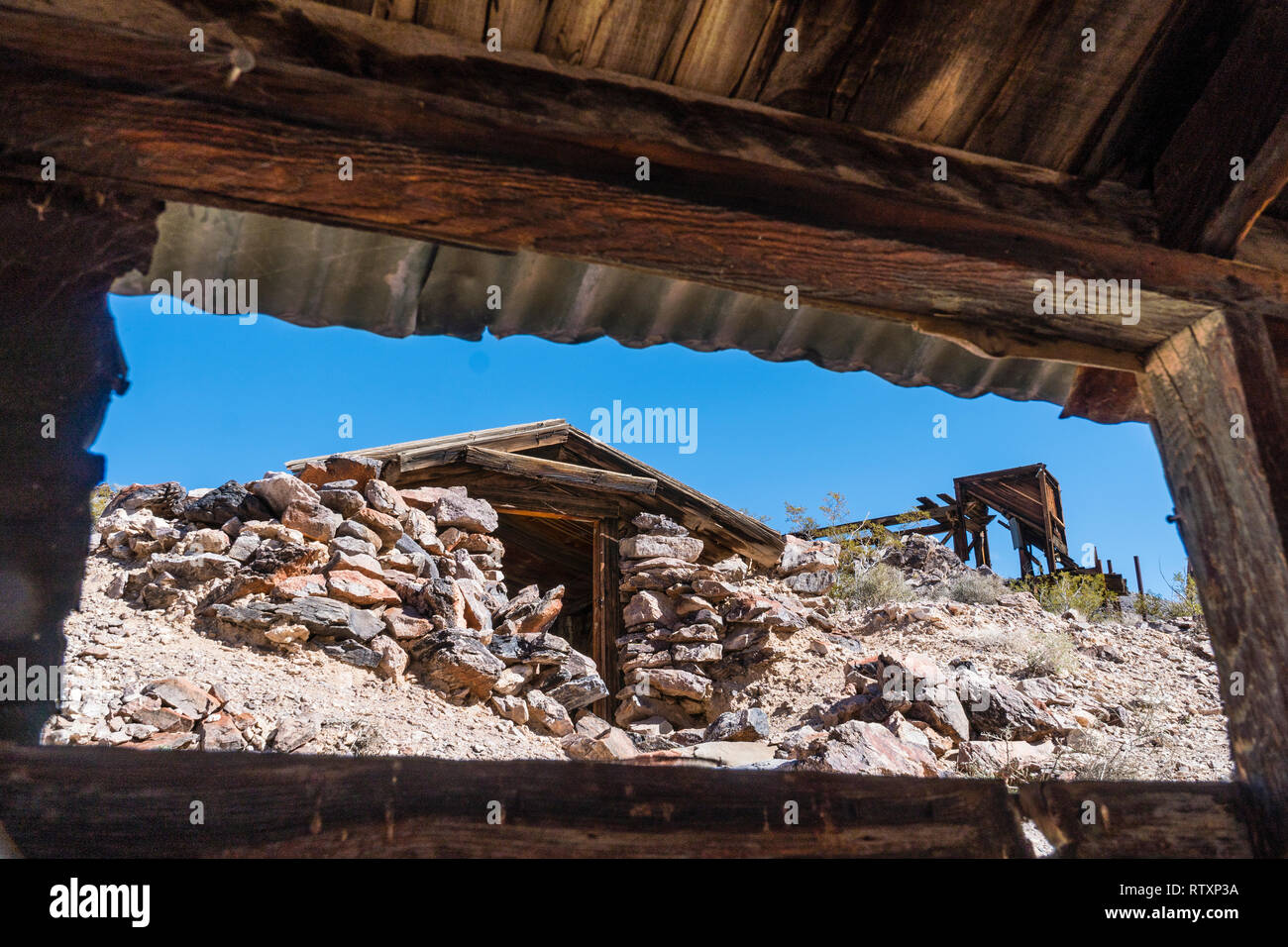 A view from inside a window of a ruin to a stone structure and a tall ...