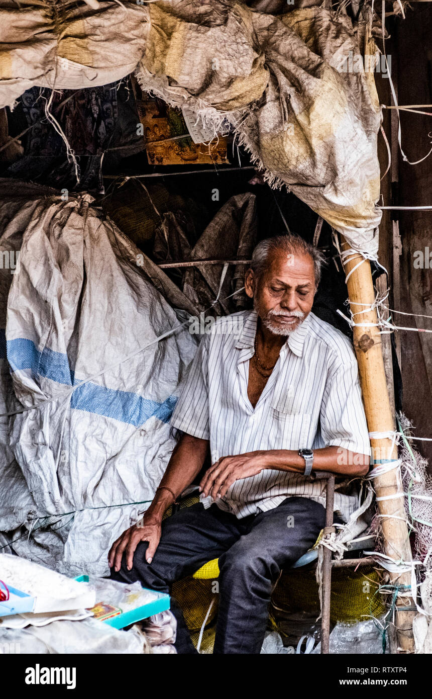 An old man at his shop selling brooms and other household equipment ...