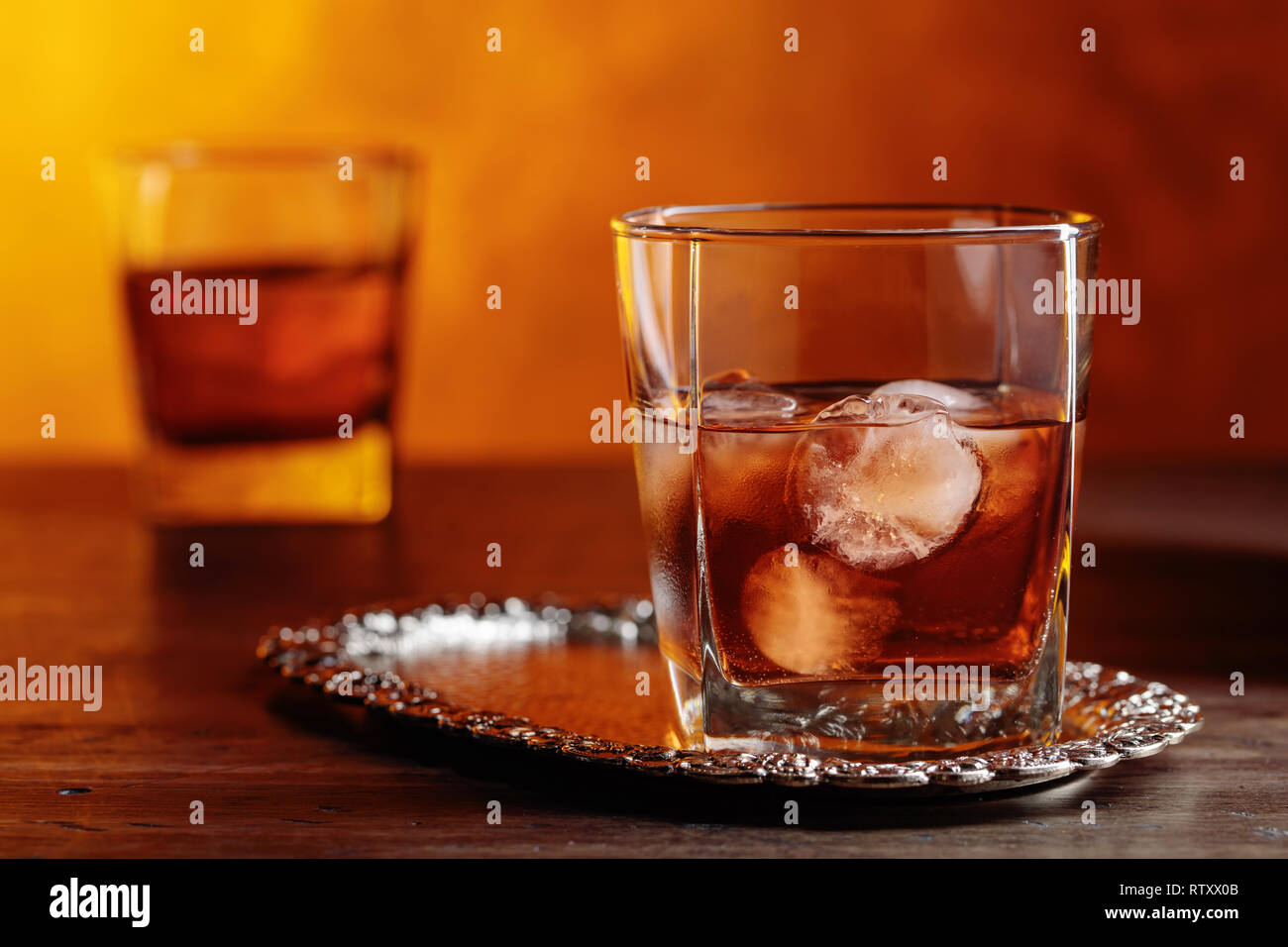 Glass of whiskey with natural ice. Color light Stock Photo - Alamy