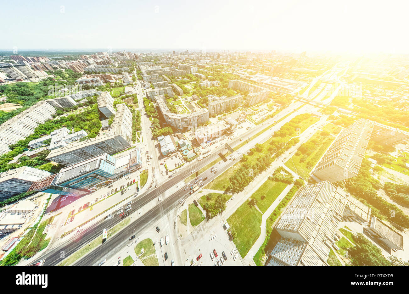 Aerial city view with crossroads and roads, houses, buildings, parks and parking lots. Sunny ...