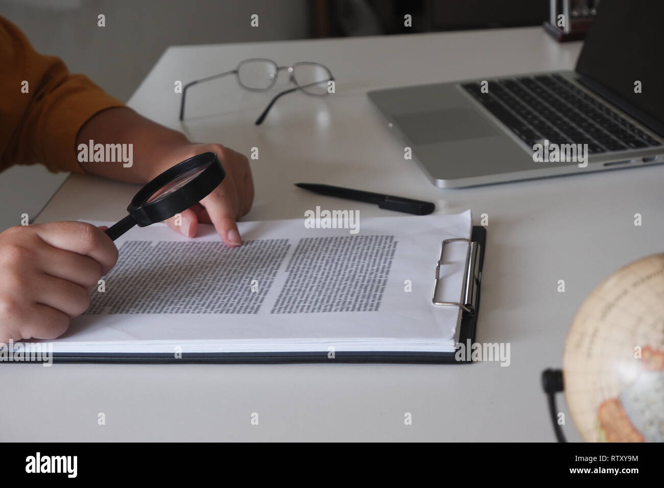 Businesswoman looking through a magnifying glass to documents note in ...