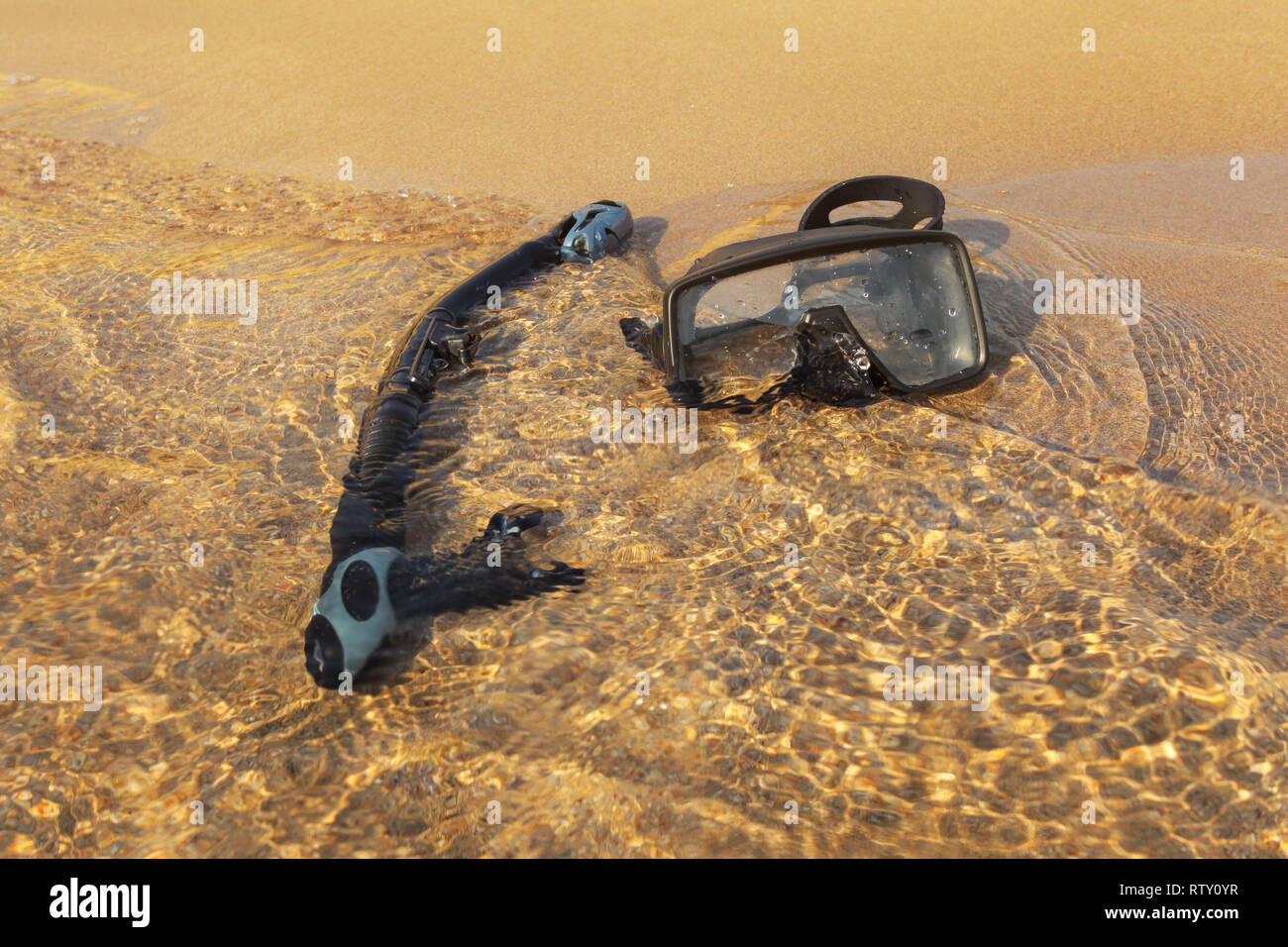 Black snorkel breathing tube and diving mask, in shallow sea on fine ...