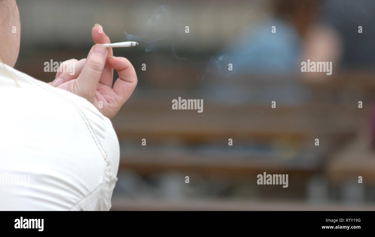 Close up woman smoking cigarette, back view. Burning cigarette in young ...