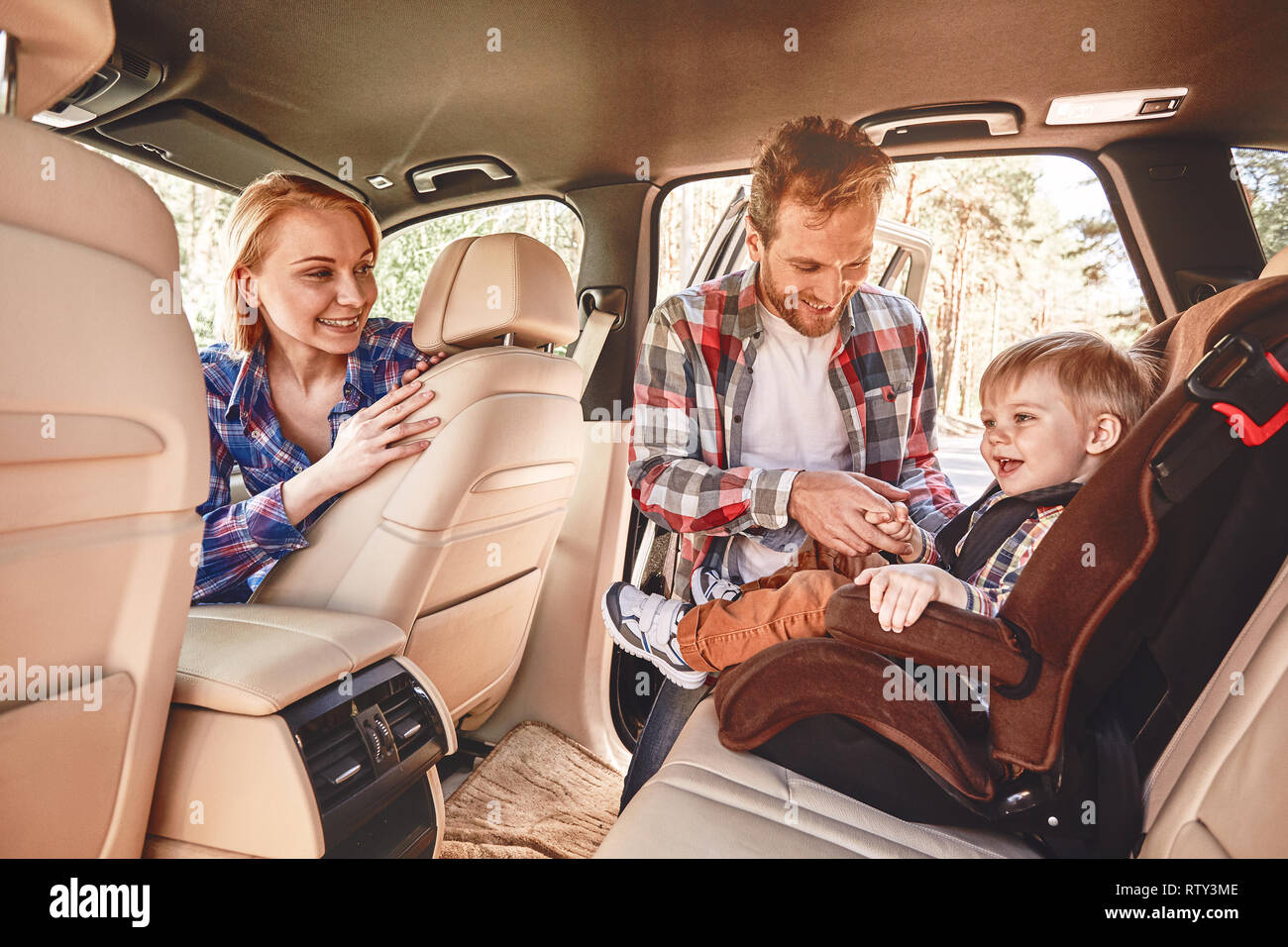 Parents trying to entertain their baby boy that sitting in a car in ...