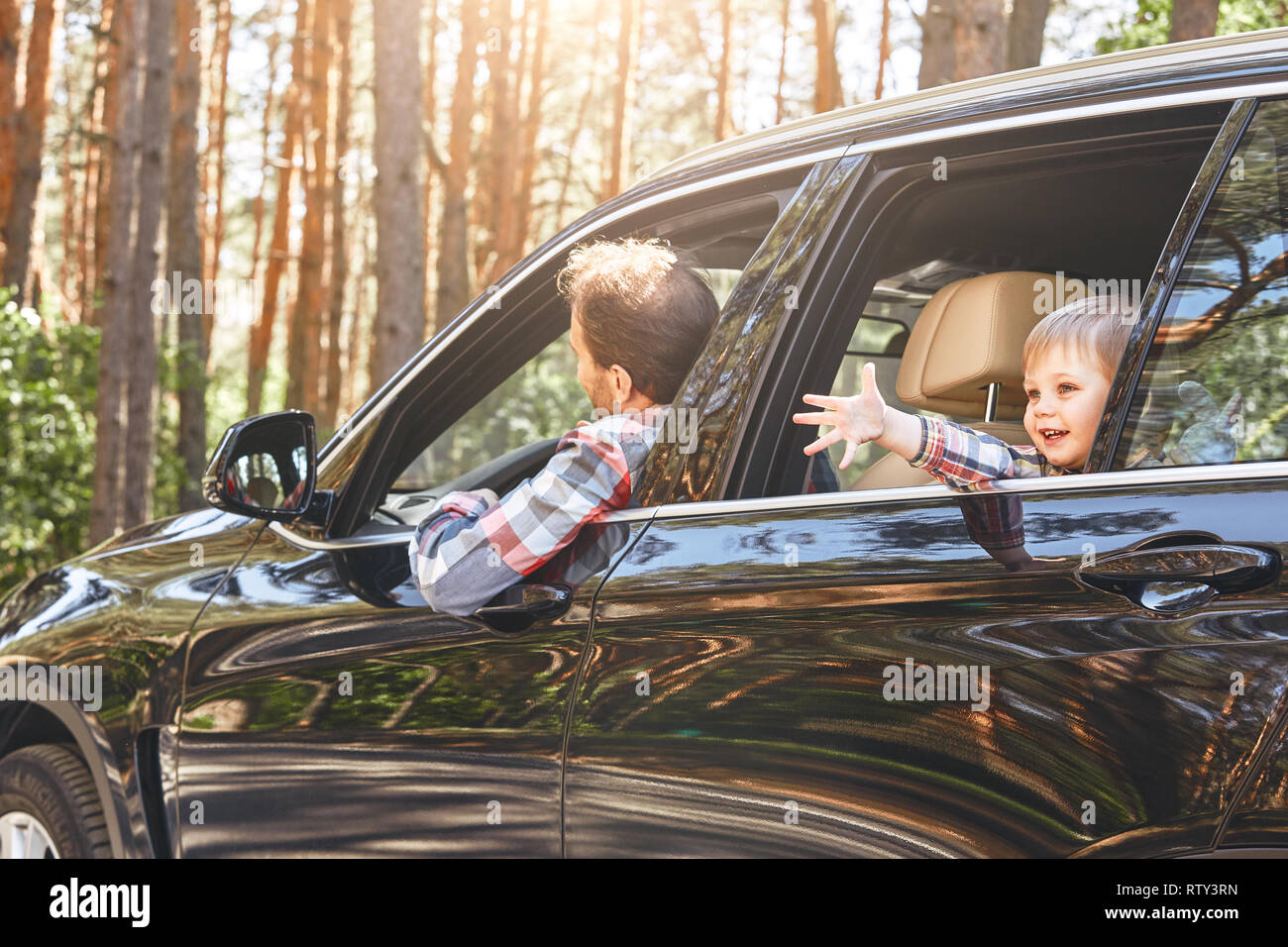 Caucasian child boy in checkered shirt looking out the window while his ...