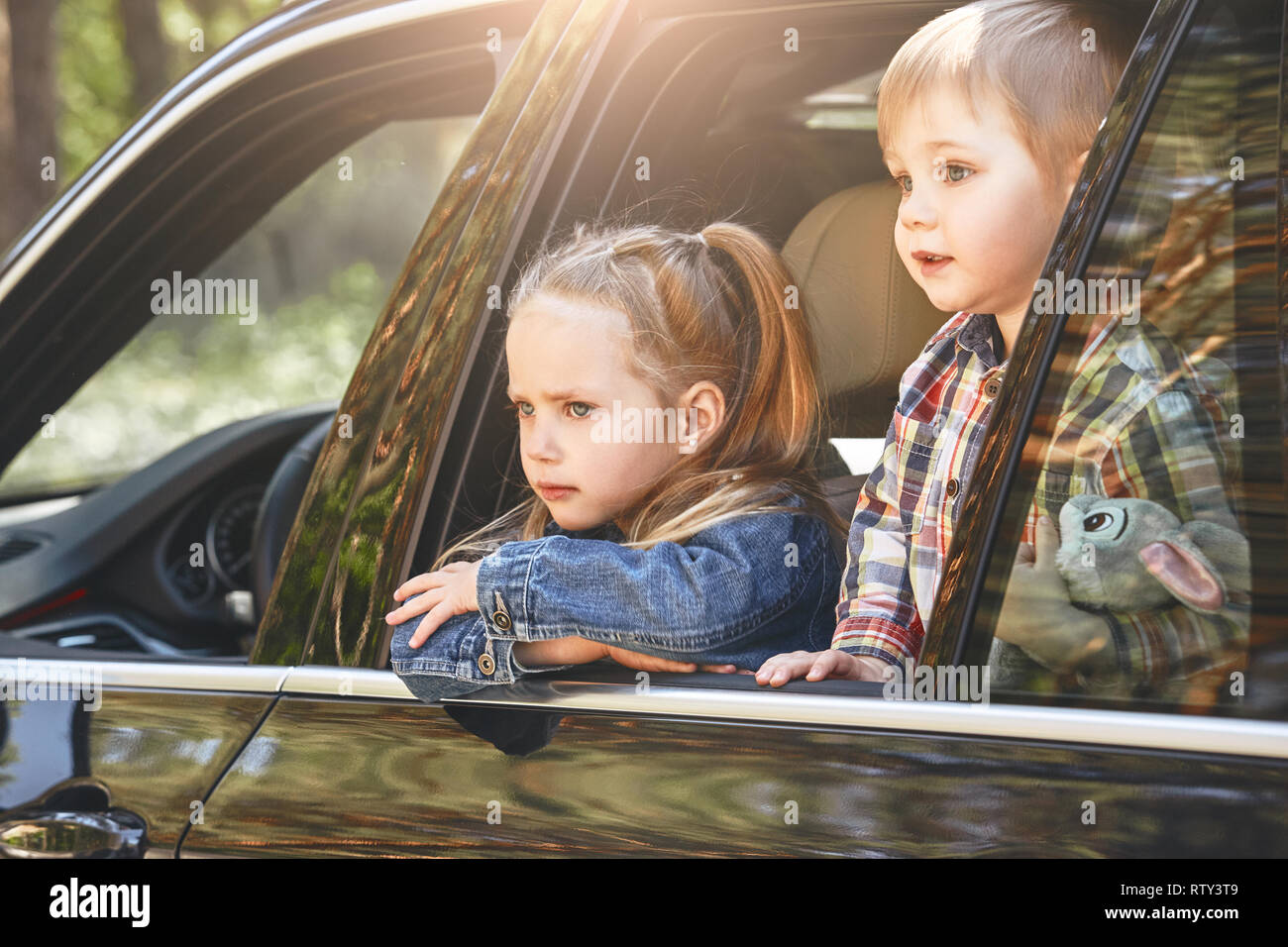 Blond caucasian children, boy and girl looking out the window while ...