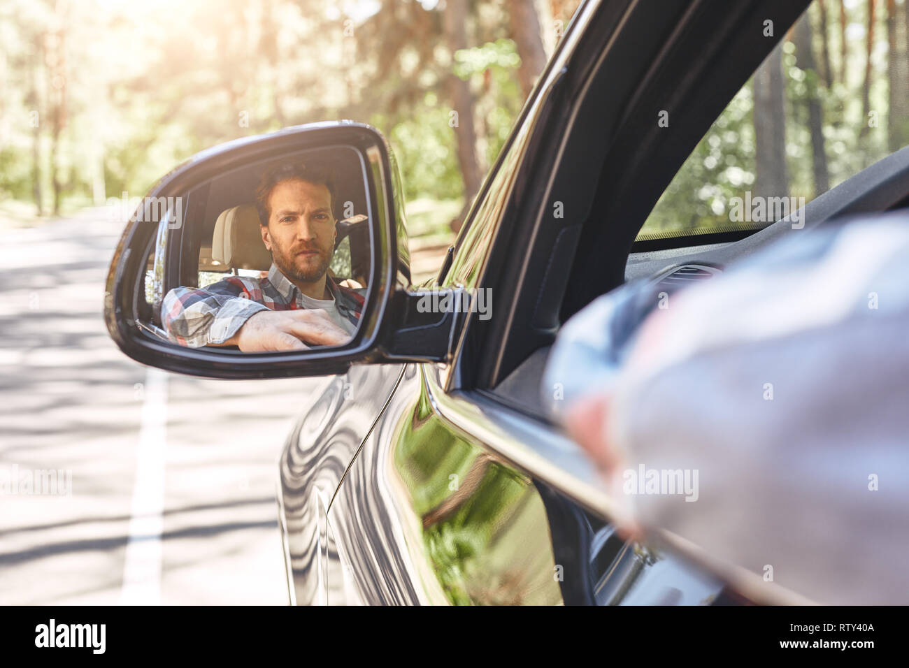 Young man driver looking in car side view mirror, making sure line is ...