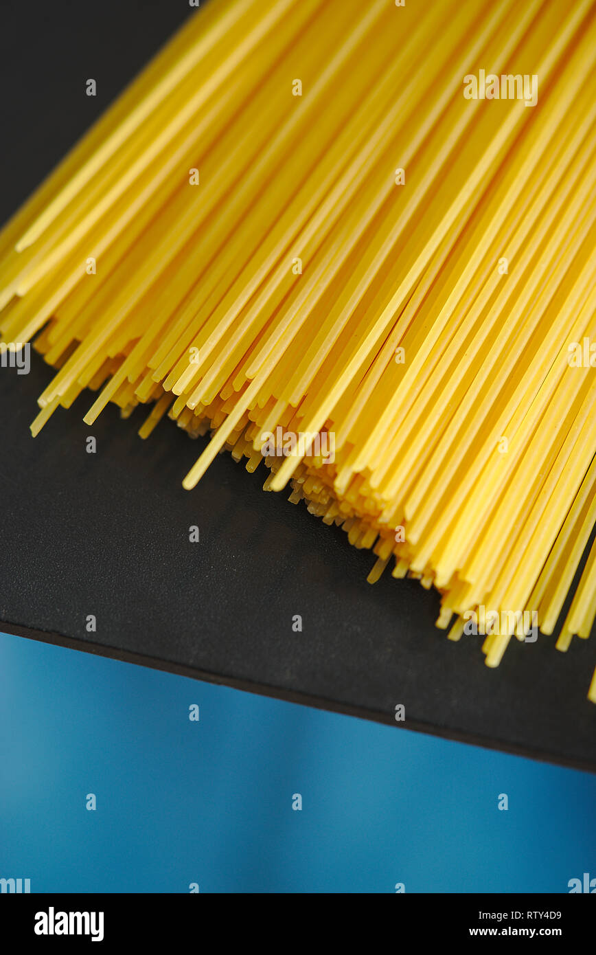 Spaghetti loose on a black table edge and blue background Stock Photo ...