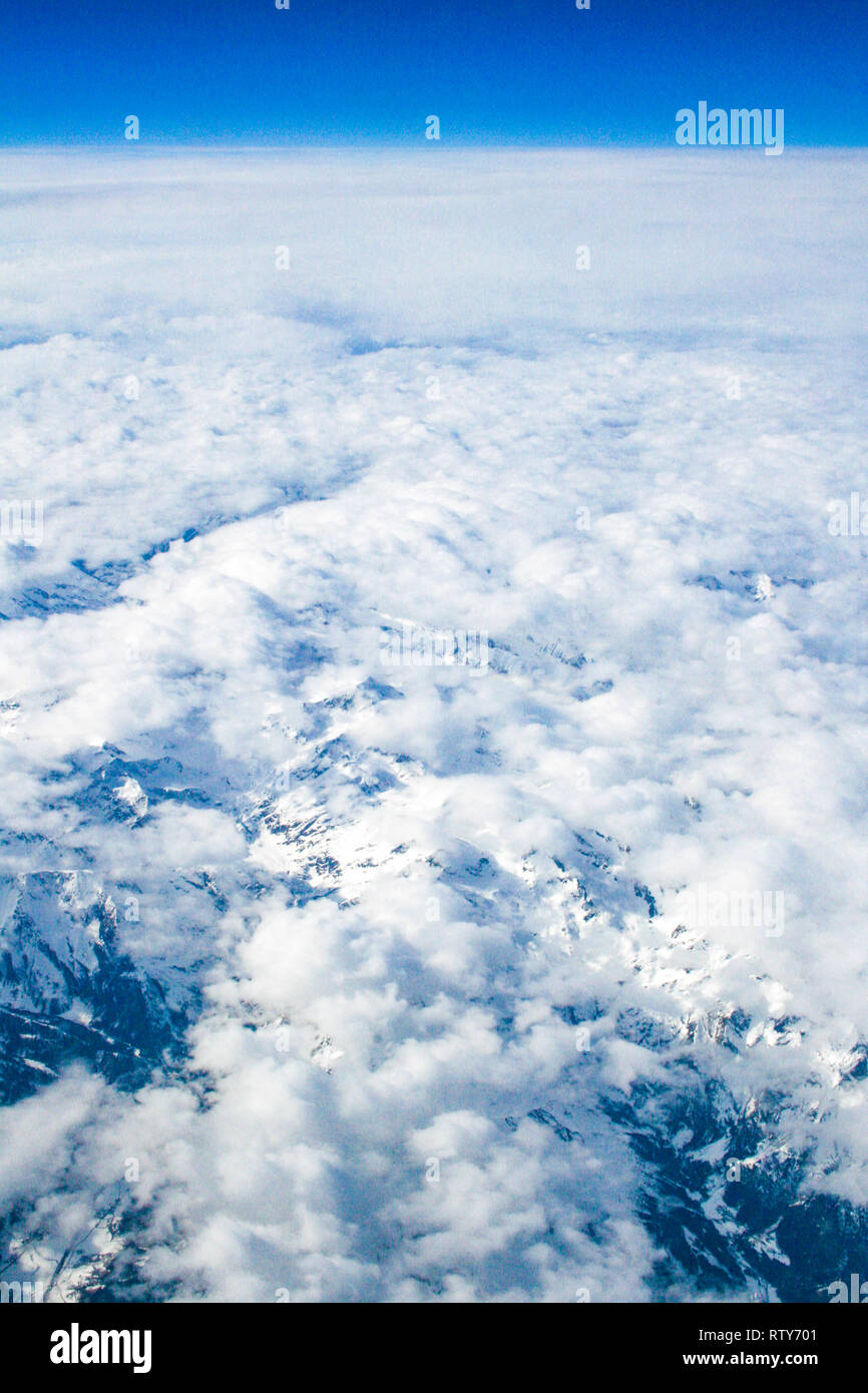 Beautiful clouds and mountains with snow, view from airplane window ...