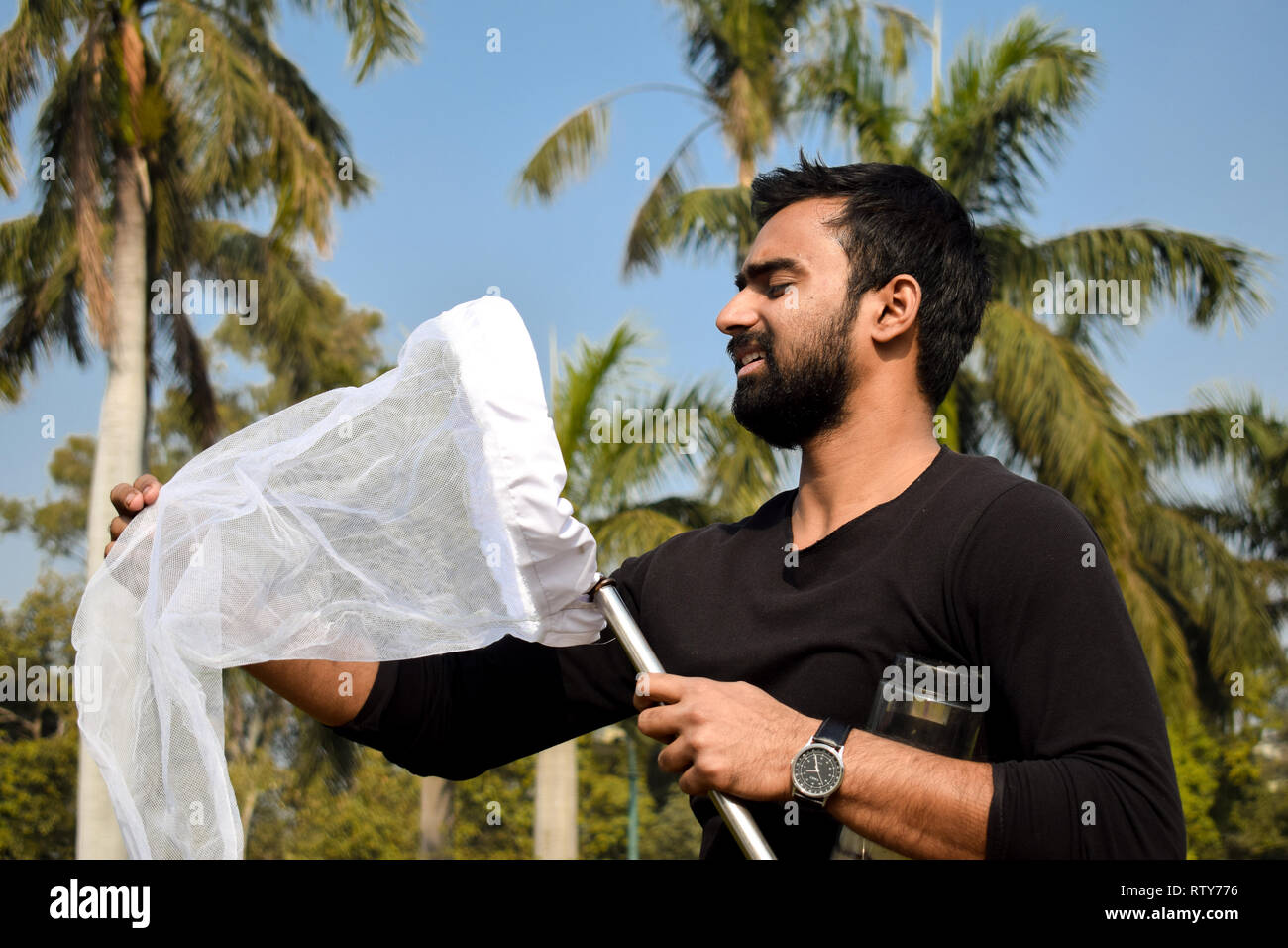 Young man entomologist collecting insects using an insect net or ...