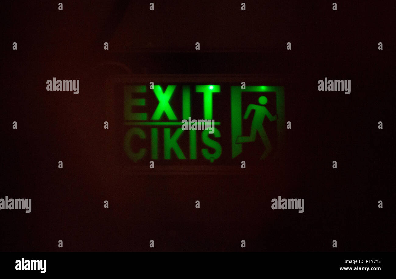 Green exit sign in English and Turkish seen in foggy interior. Concepts ...