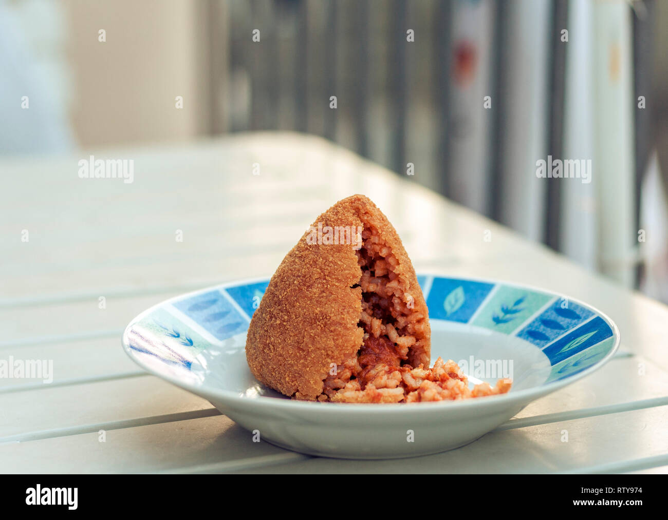 Sicilian snack, fried ball of rice arancino on a plate, tipical street ...