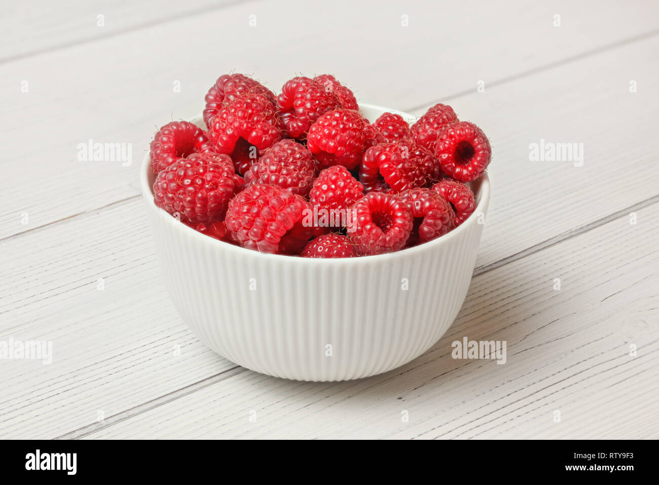 Small white ceramic bowl full of freshly picked raspberries, light ...