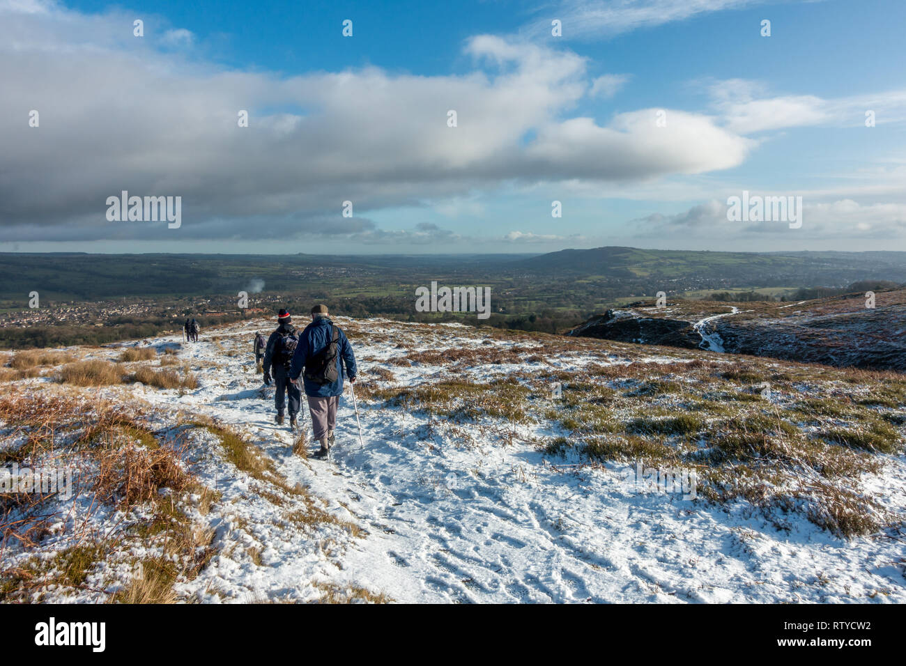 Group of ramblers walking above Burley-in-Wharfedale village on a snowy ...