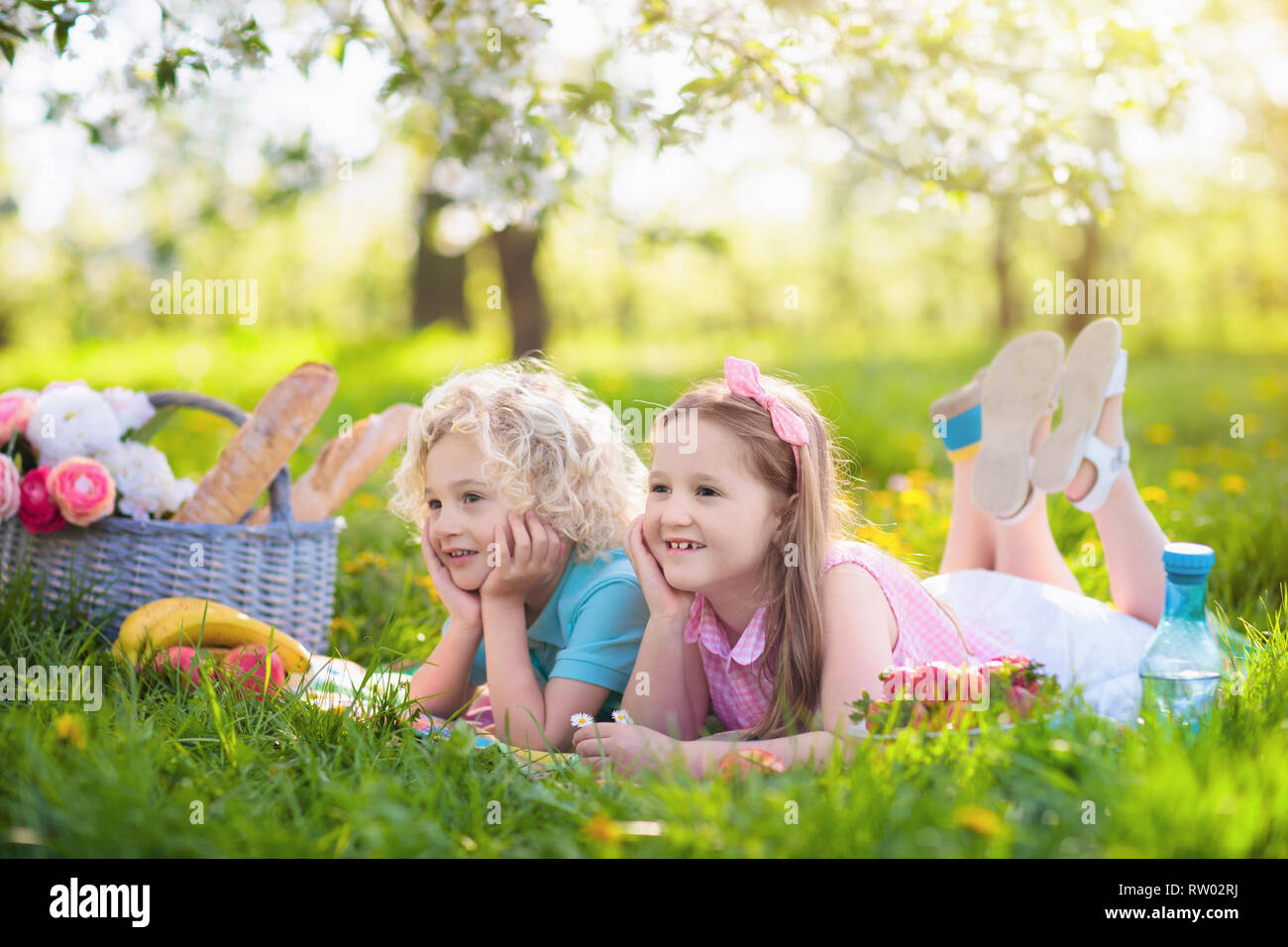 Family picnic in spring park with blooming cherry trees. Kids eating ...