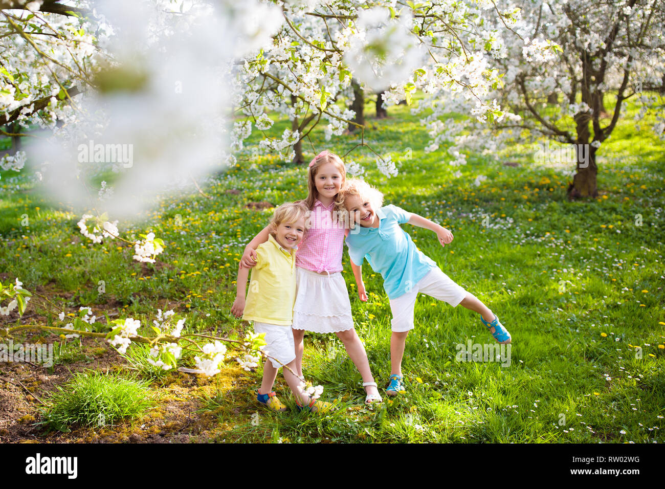 Kids playing in spring park. Children running in sunny garden with ...