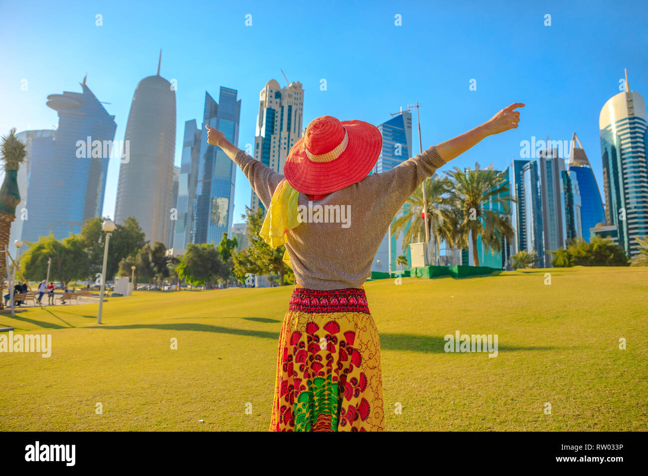 Travel in Qatar. Happy woman with sunhat in a park along Corniche ...