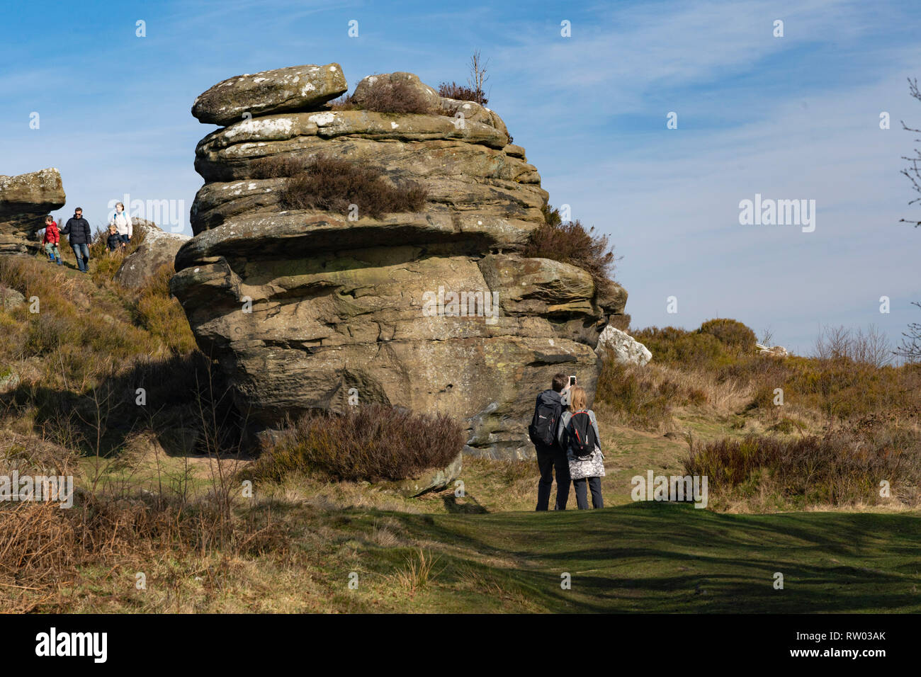 A couple taking a photograph of a large rock formation with their ...