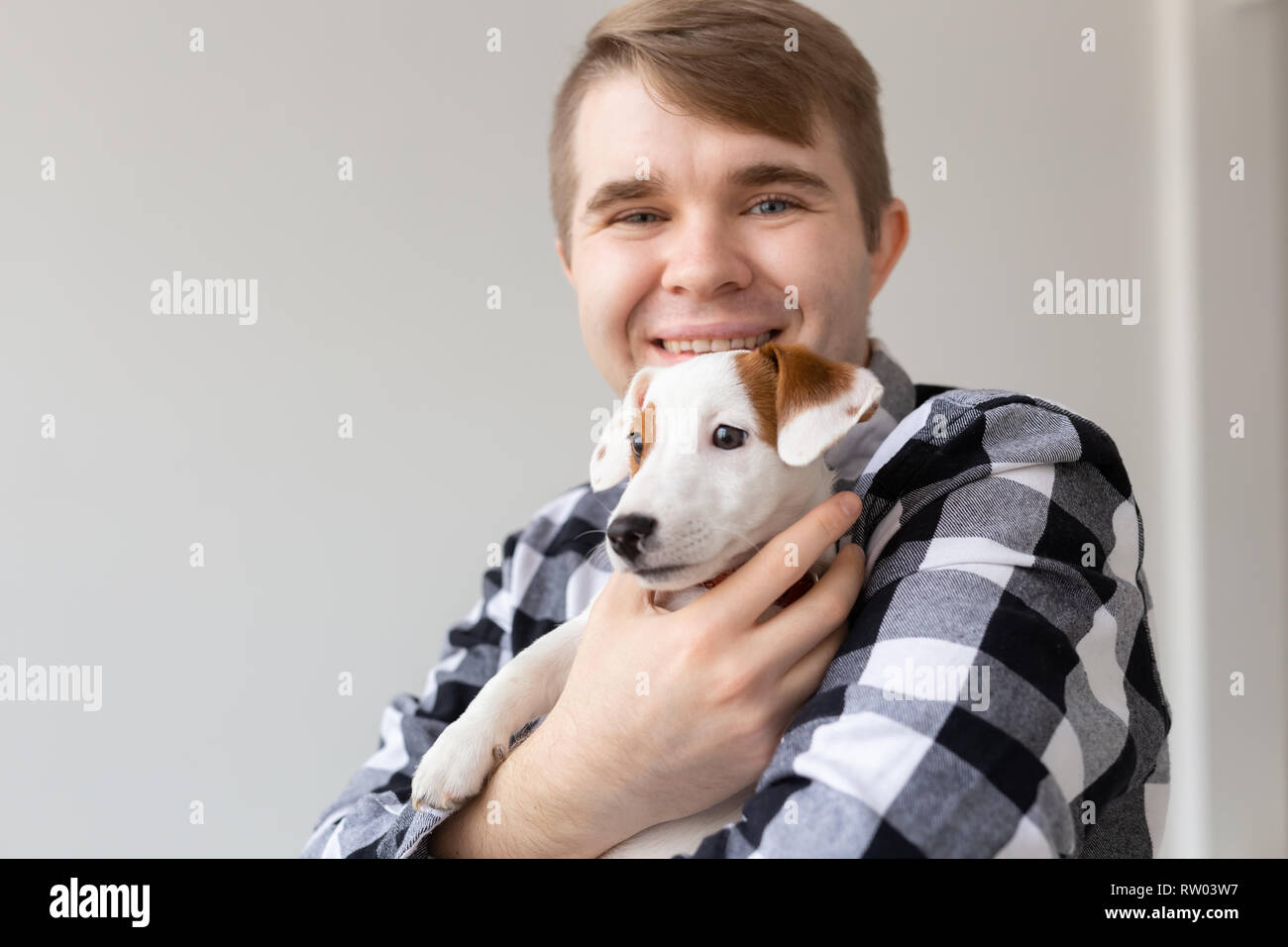 people, pets and animals concept - young man hugging jack russell ...