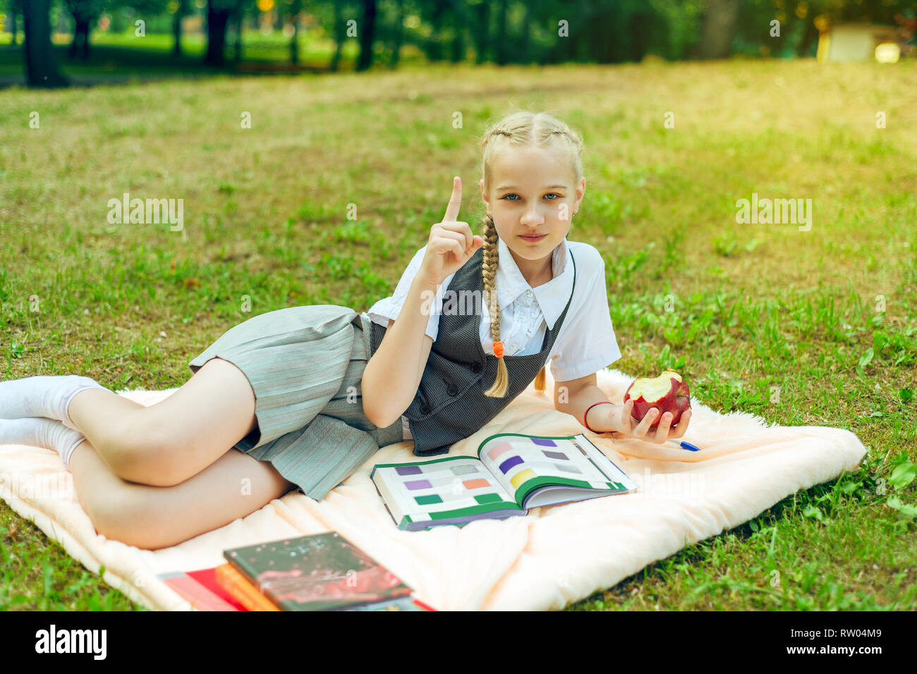 schoolgirl in uniform shows finger number one up, sign of attention ...