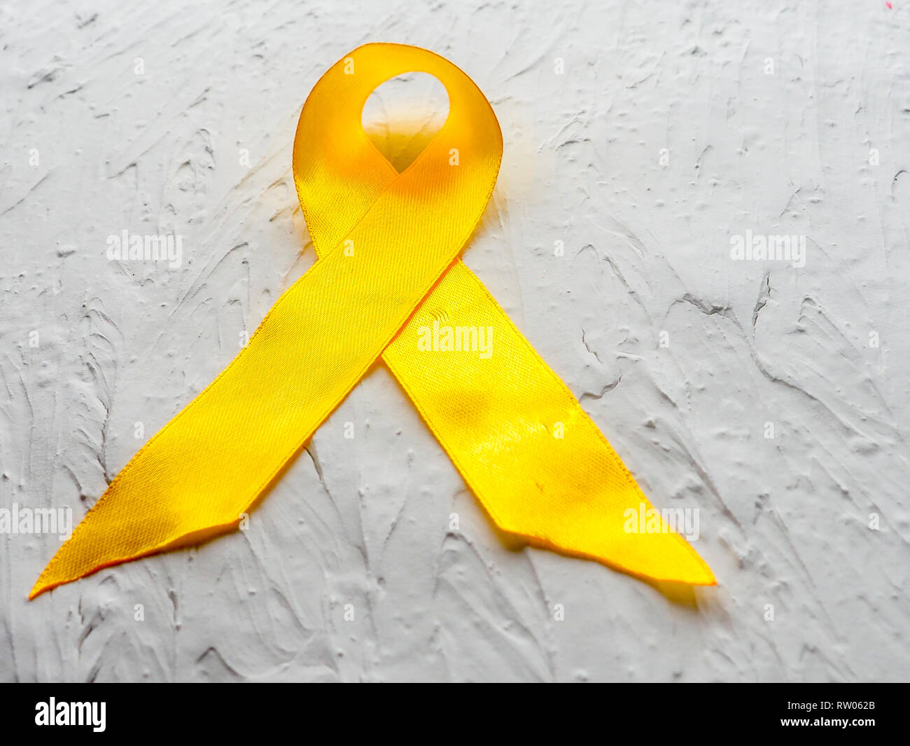Yellow awareness ribbon on white textured background Stock Photo - Alamy