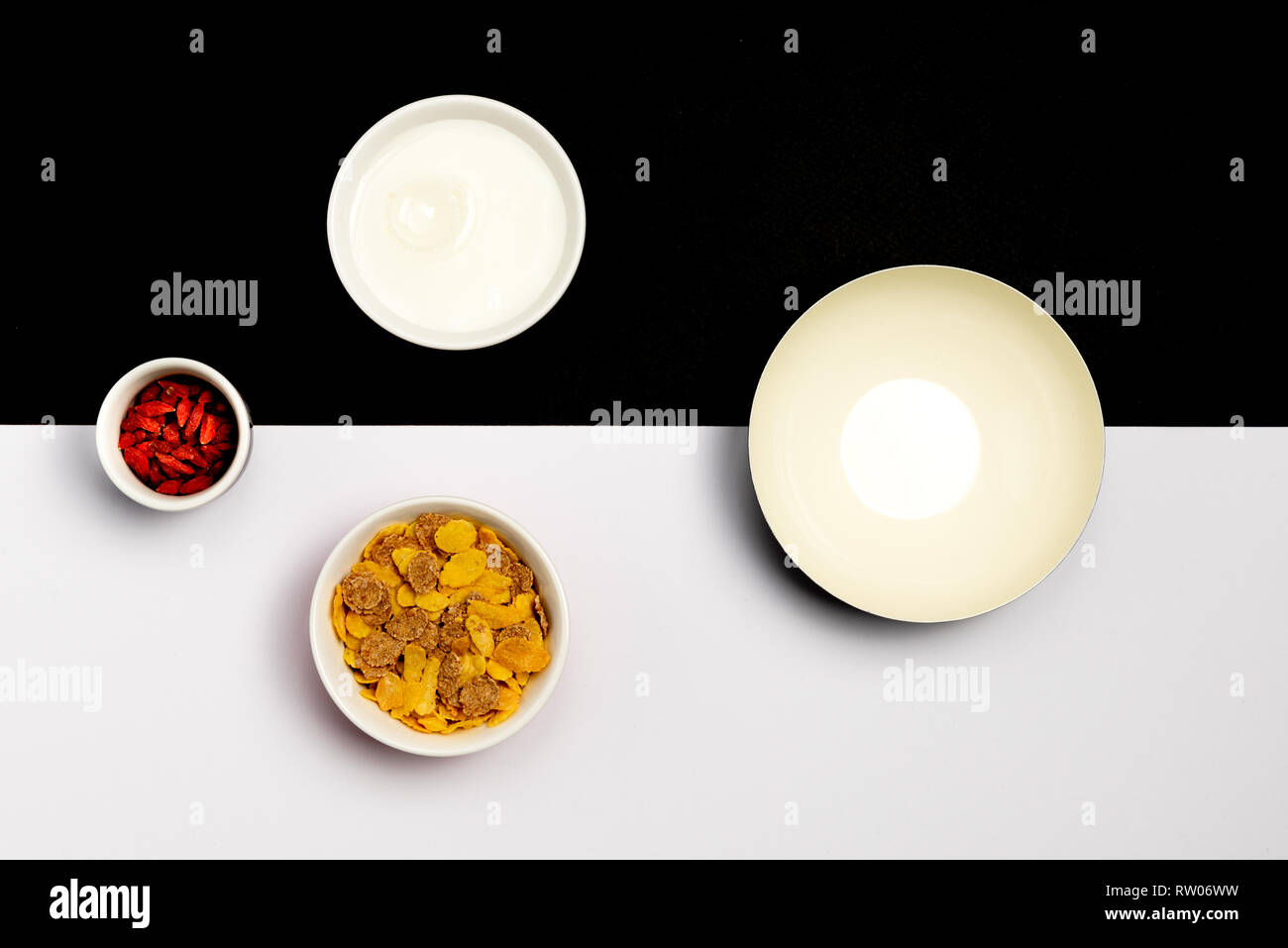 Group of empty ceramic bowls filled with milk, cereal and dry goji ...