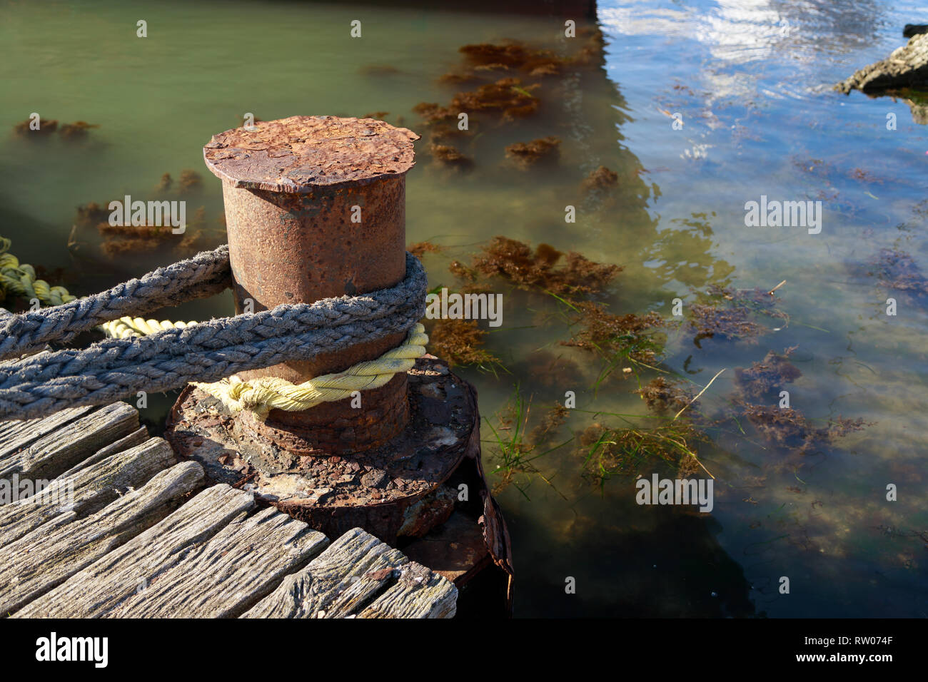 Rope is tied to an old rusty pillar of a dilapidated wooden jetty Stock ...