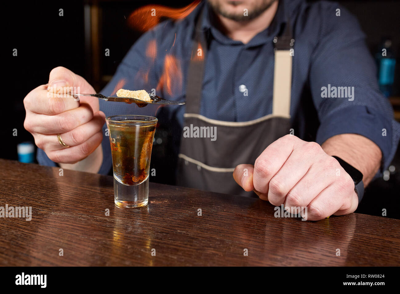 Fiery show at the bar. The bartender makes hot alcoholic cocktail and ...