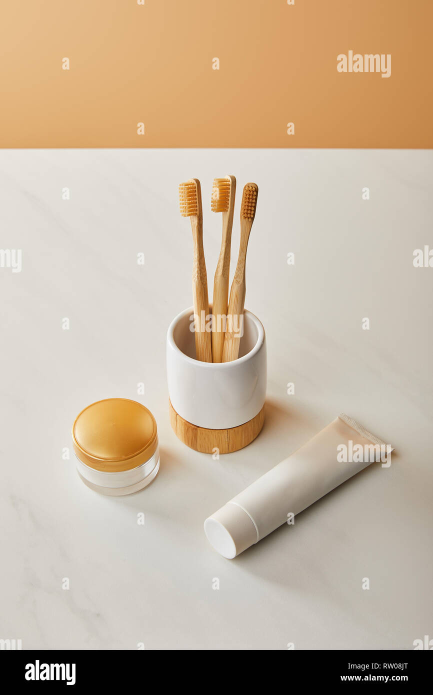 holder with bamboo toothbrushes, toothpaste in tube and cosmetic cream ...