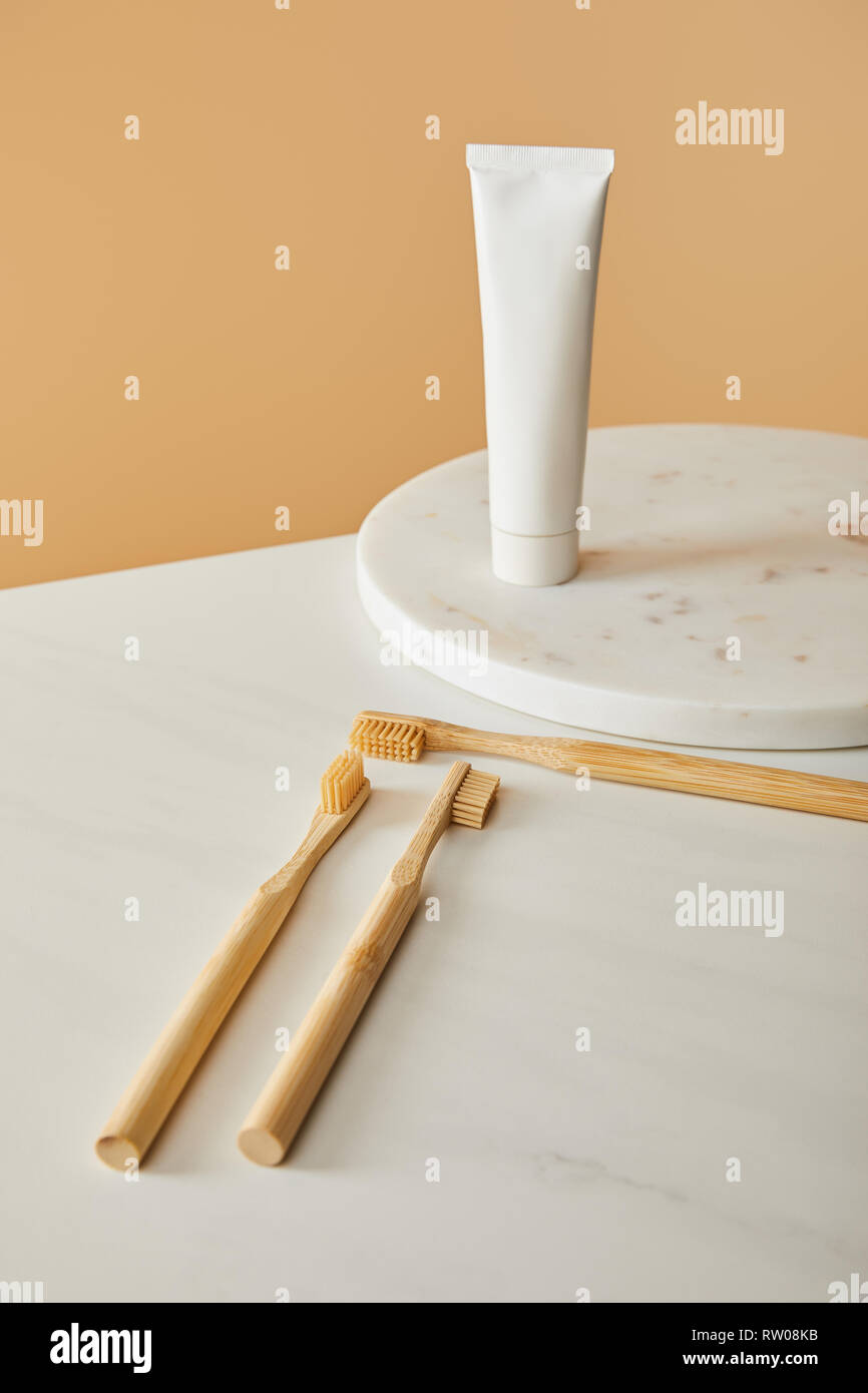 marble round board with toothpaste in tube and bamboo toothbrushes on ...