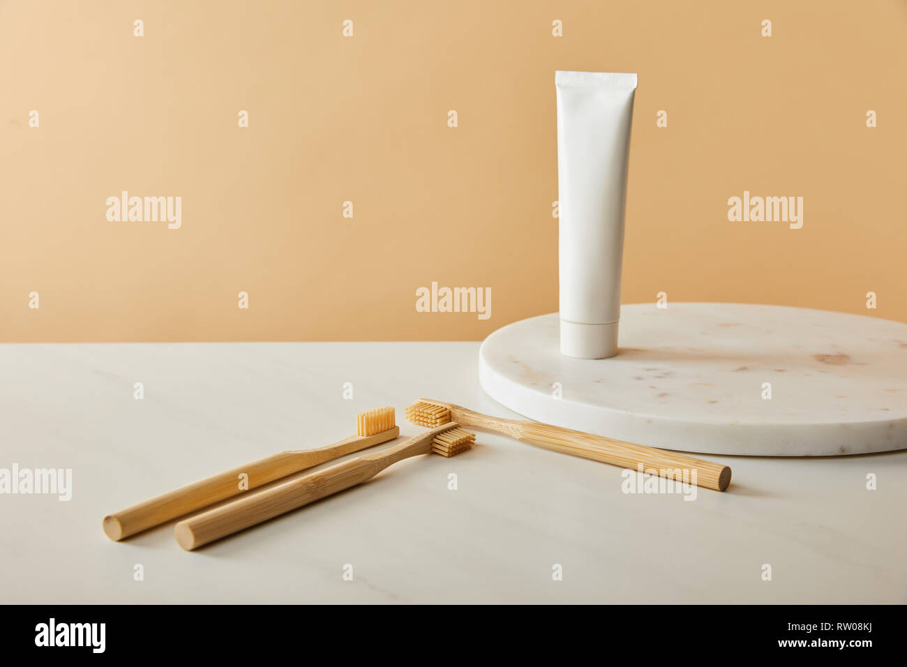 marble round board with toothpaste in tube and bamboo toothbrushes on ...