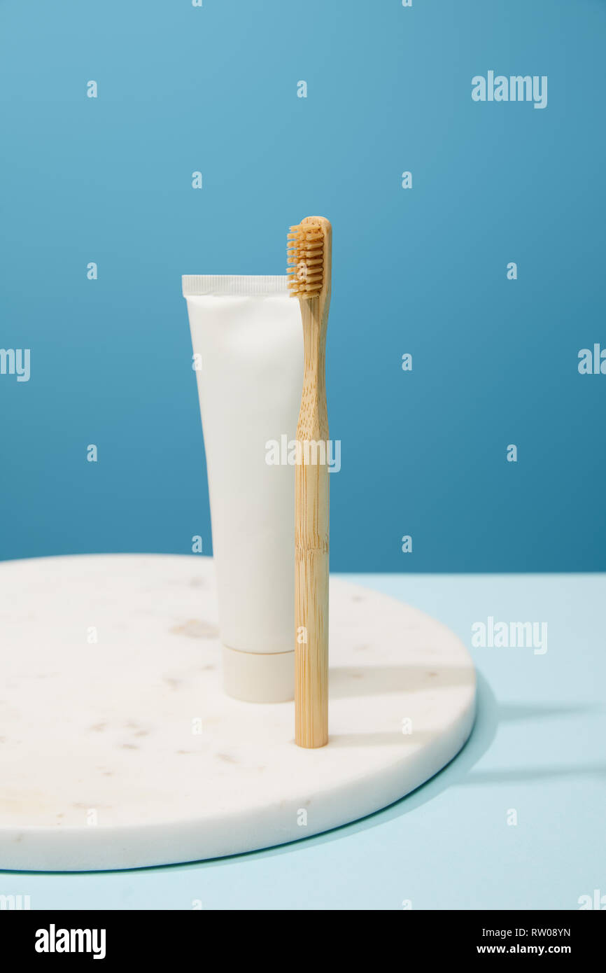 white marble round board with bamboo toothpaste in tube and toothbrush ...