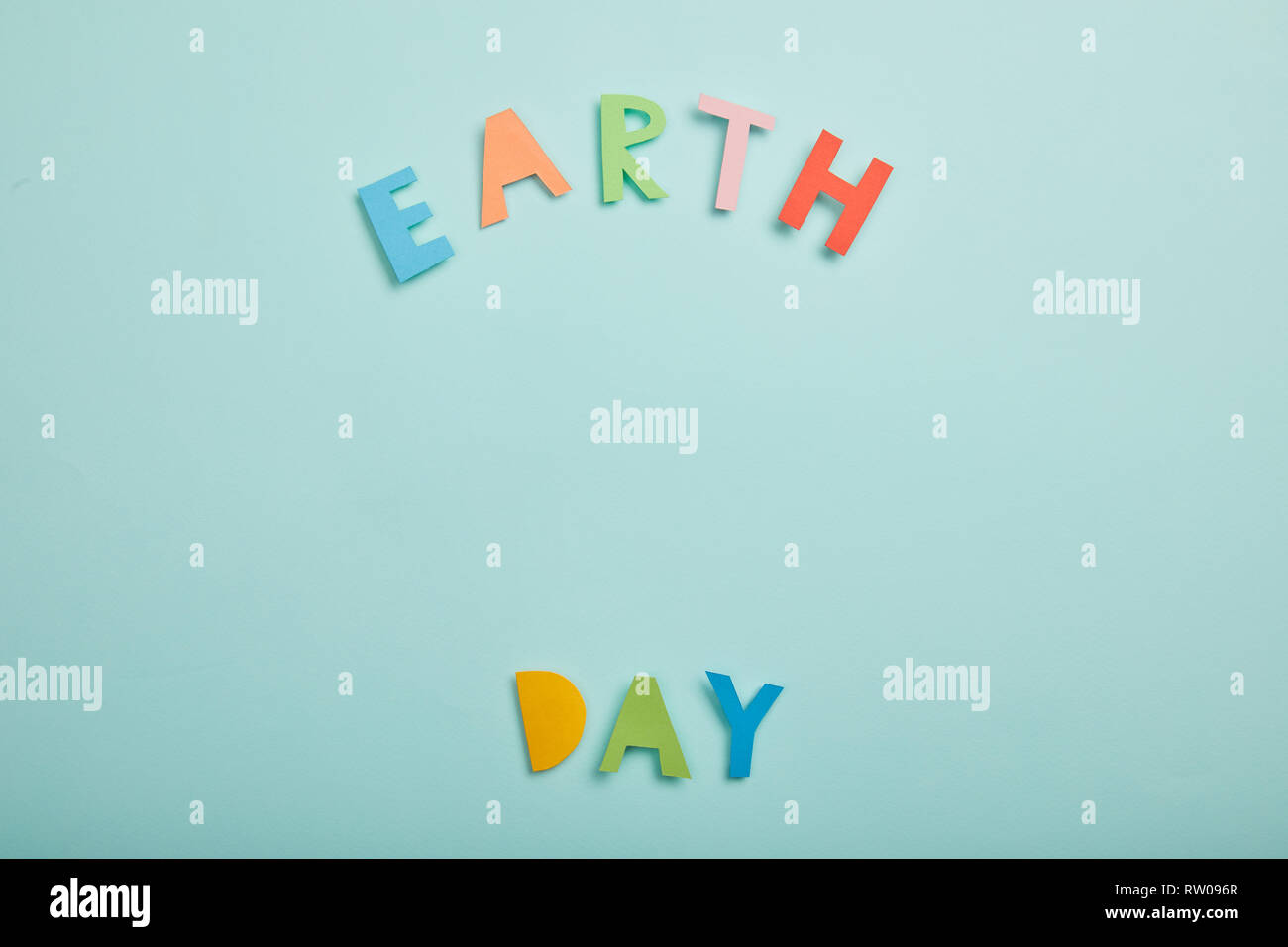 top view of colorful paper letters on turquoise background, earth day ...