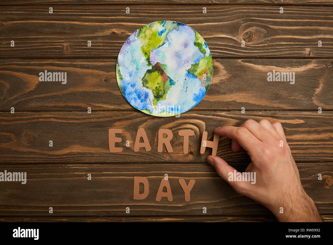 partial view of woman holding paper letters and planet picture on brown ...