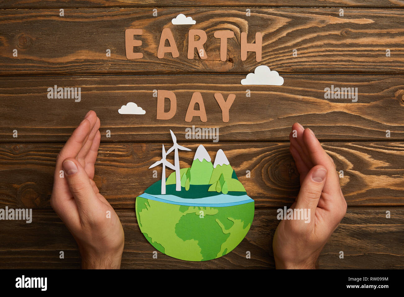 partial view of woman holding paper cut planet with renewable energy ...