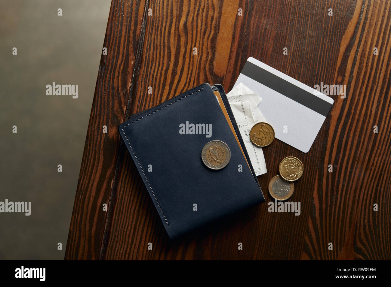 top view of wallet with credit card, coins and cheque on wooden table ...