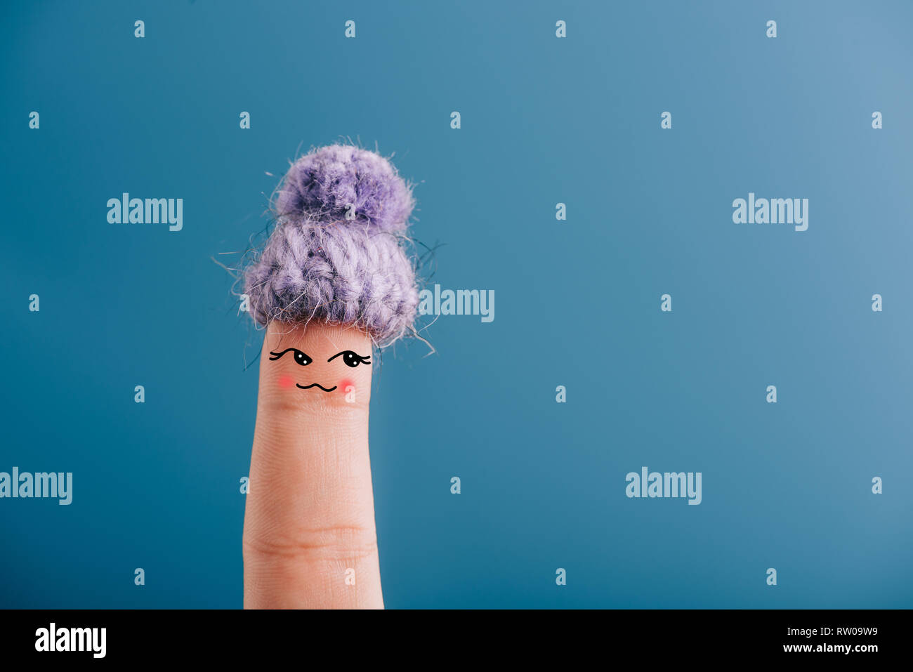 cropped view of one finger in knitted hat isolated on blue Stock Photo ...