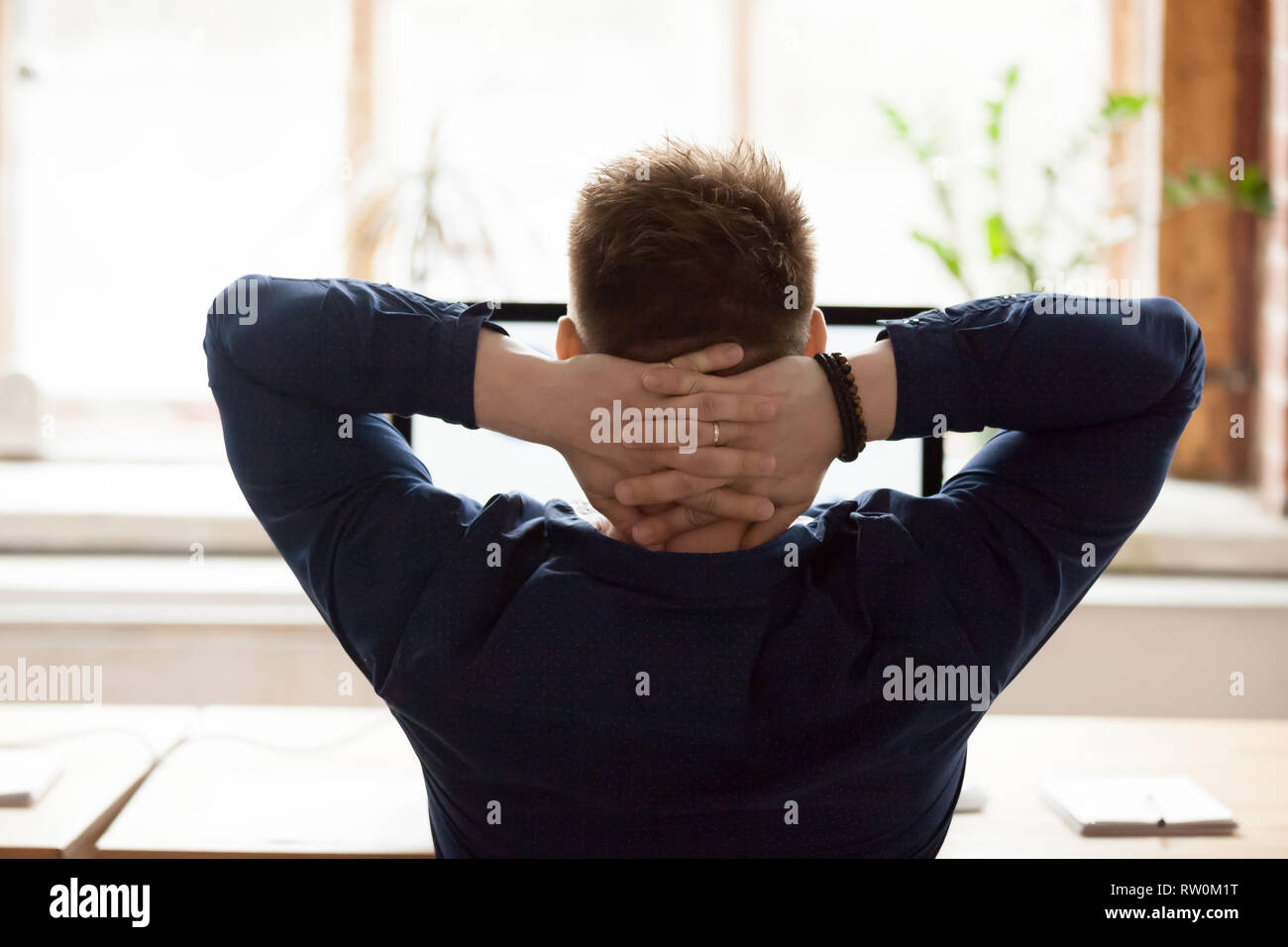 Rear view businessman sitting on chair putting hands behind head Stock ...