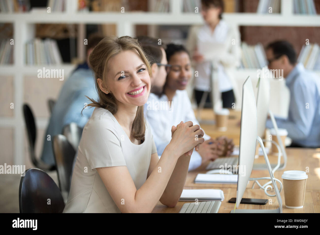 Employee female sitting at desk opposite pc looking at camera Stock ...