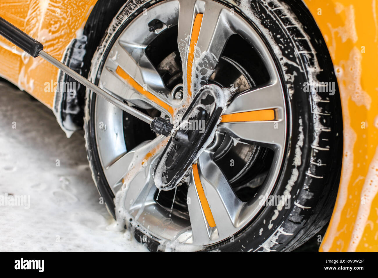 Yellow car wheel washed in self service carwash, brush cleaning ...