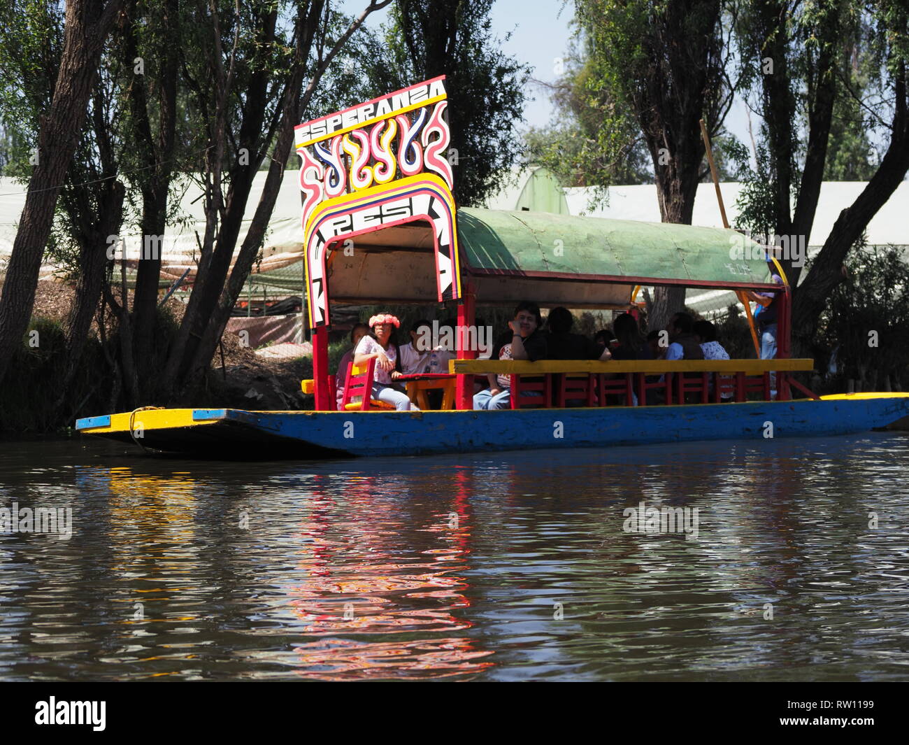 One colorful boat with tourists and gondolier at Floating Gardens in ...