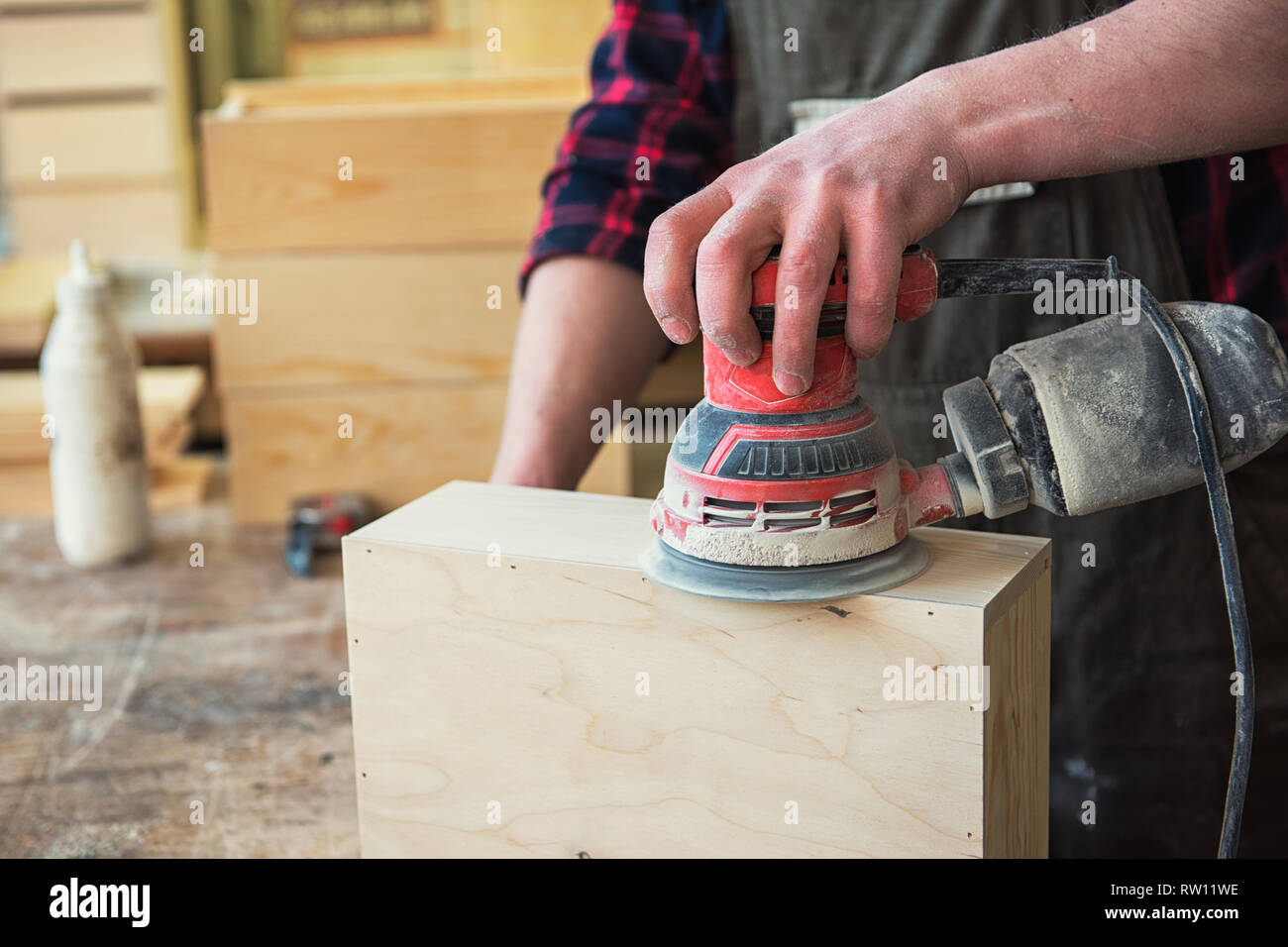 Worker grinds the wood box of angular grinding machine. Profession ...