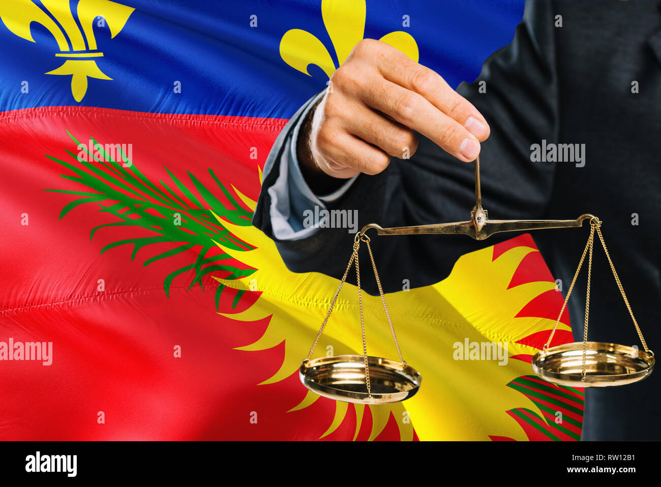 Judge is holding golden scales of justice with Guadeloupe waving flag ...