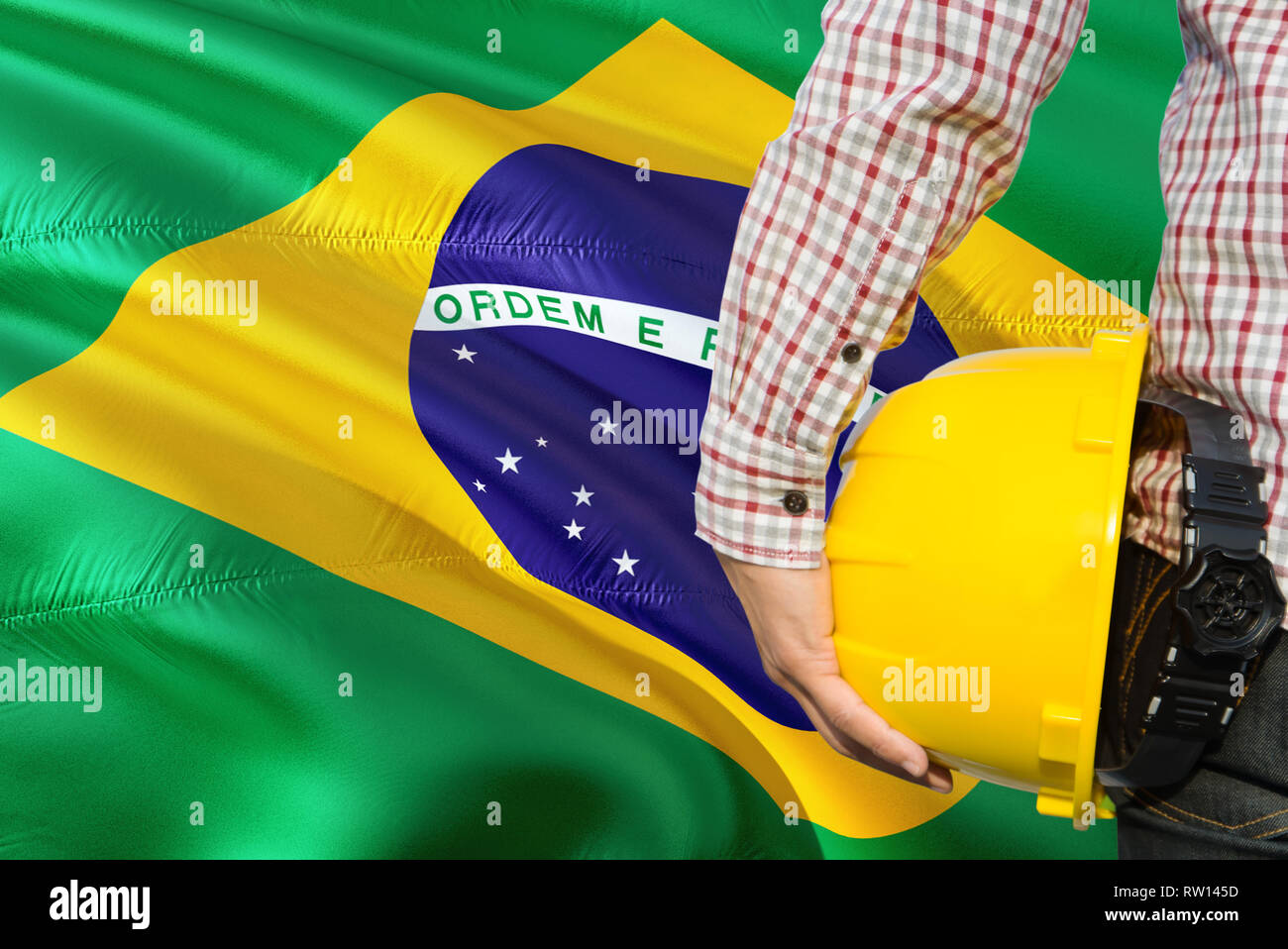 Brazilian Engineer is holding yellow safety helmet with waving Brazil ...