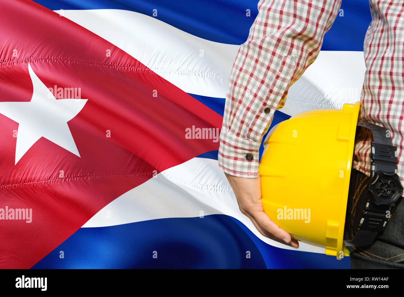 Cuban Engineer is holding yellow safety helmet with waving Cuba flag ...
