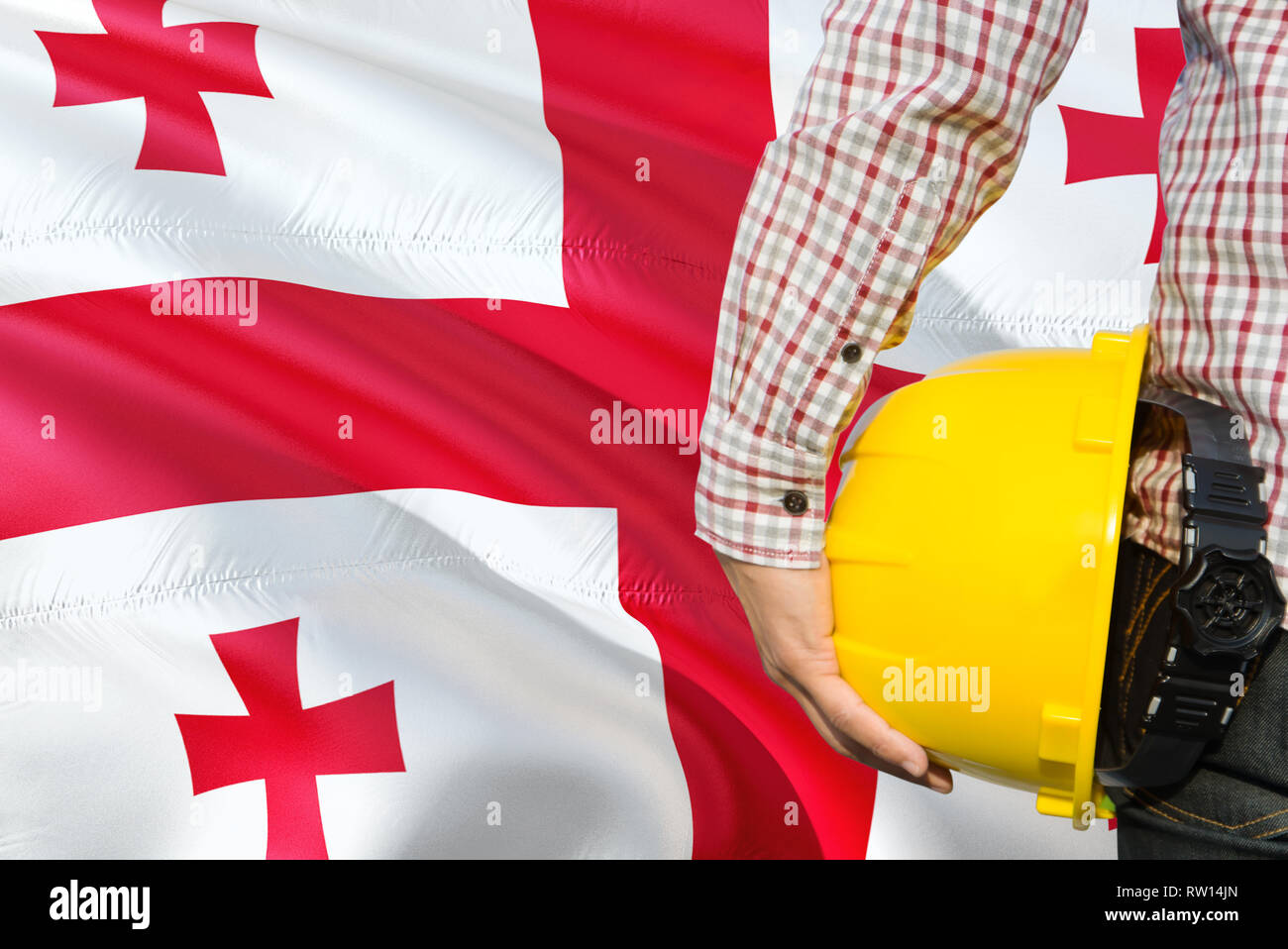 Georgian Engineer is holding yellow safety helmet with waving Georgia ...